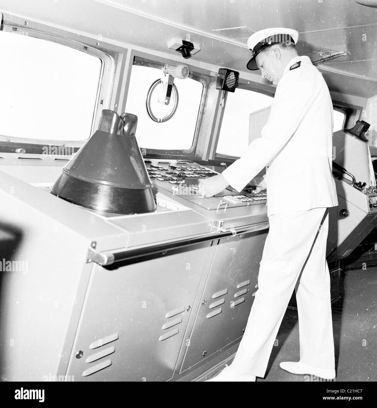 1950s. A uniformed Captain stands at the ship's control desk on the ...