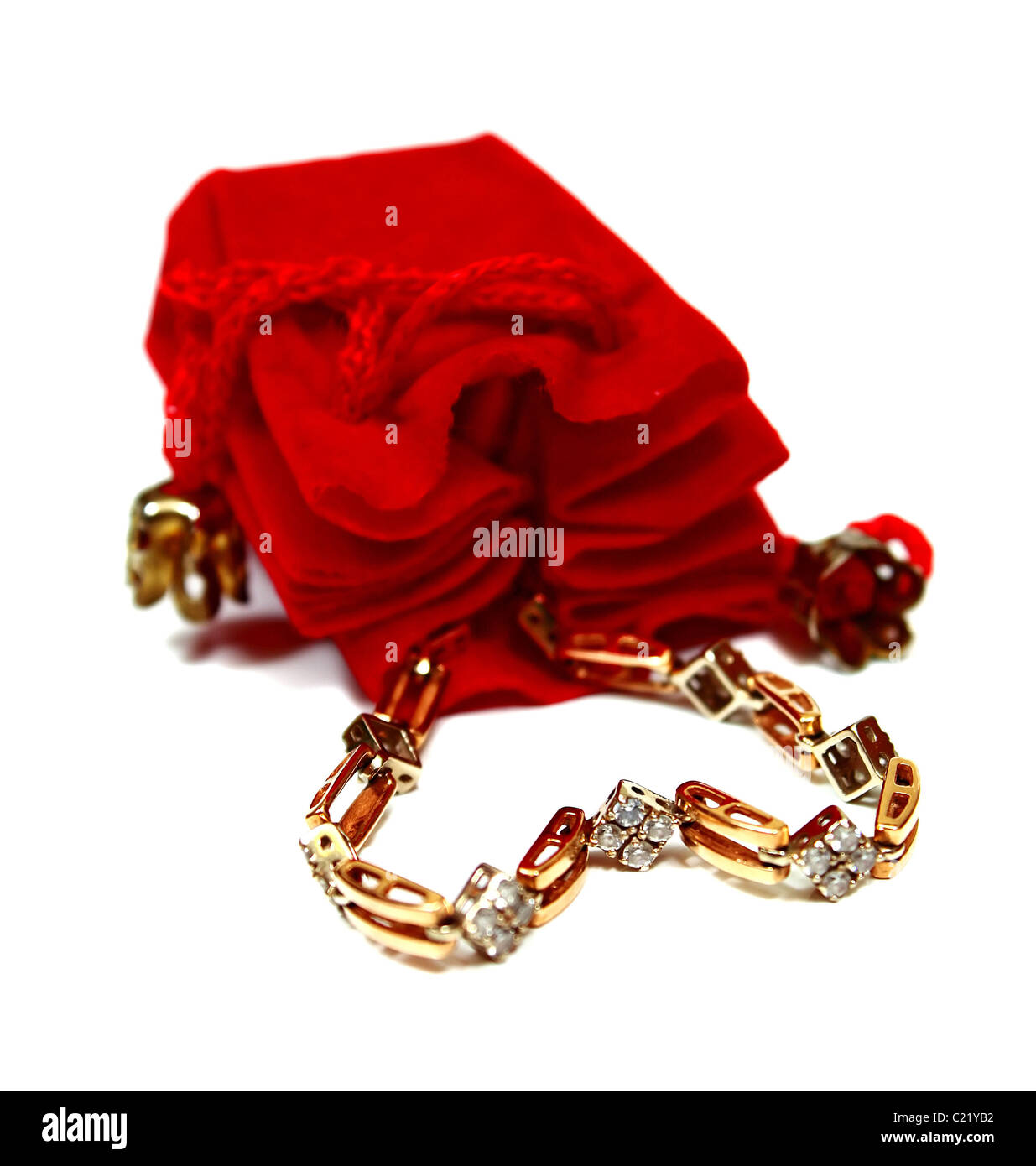 red sac for a gift and gold bangle with stones isolated on white ...