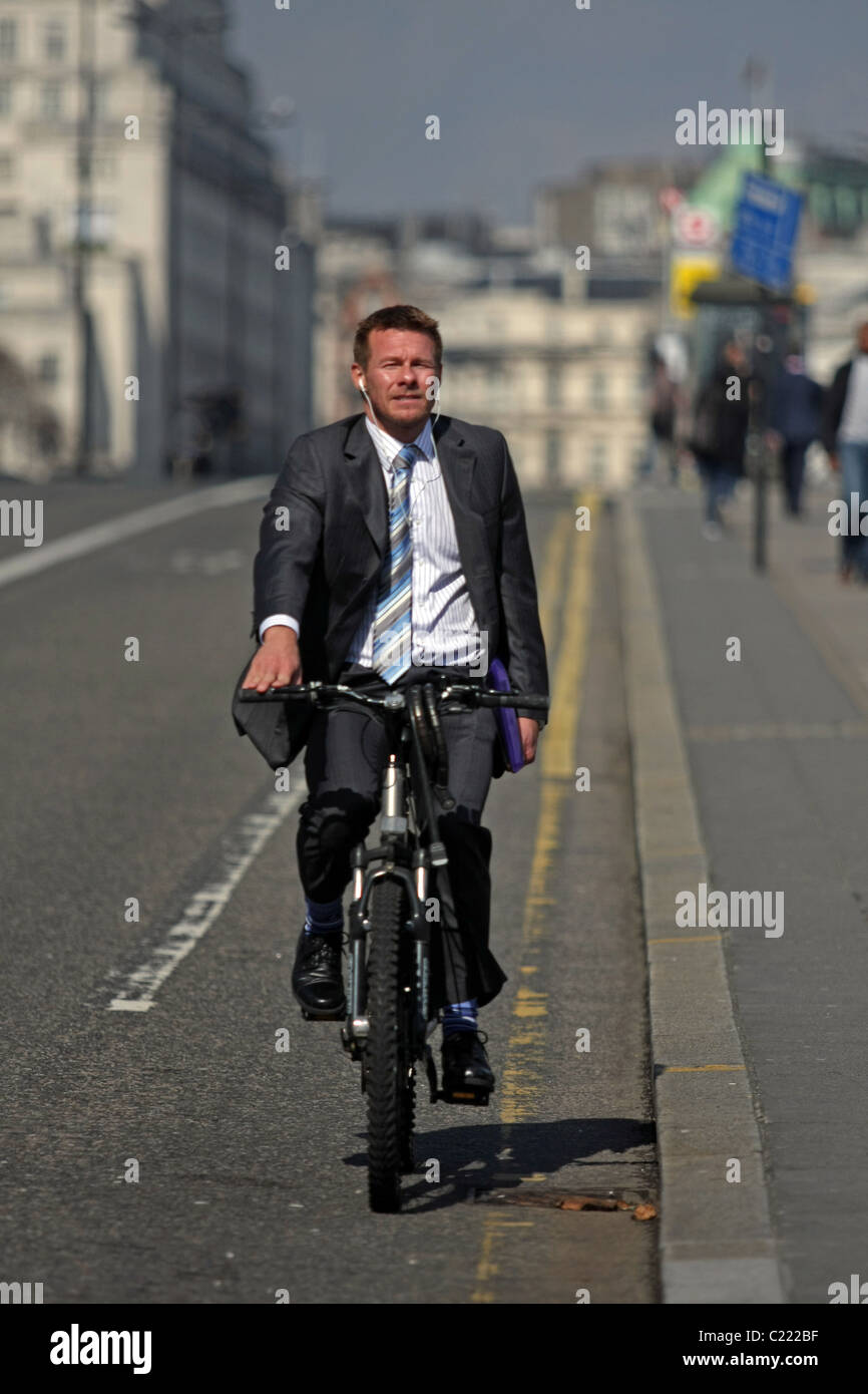A man cycling in London, on a sunny day, with only one hand holding the ...