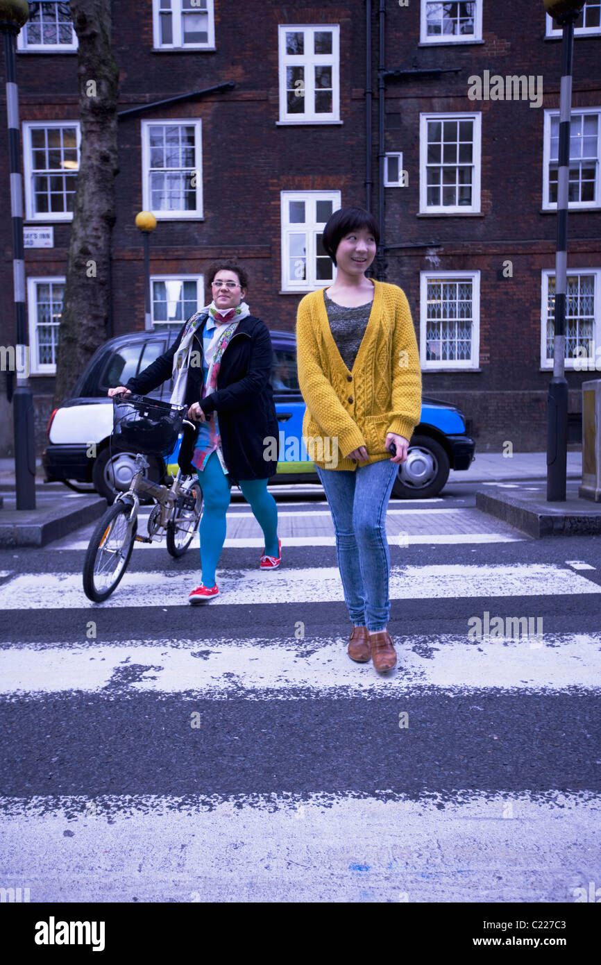 Two female adults walking across the zebra crossing Stock Photo - Alamy