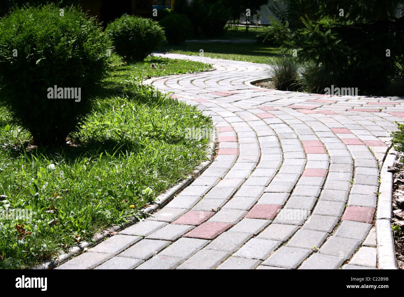 A stone walkway winding its way through a tranquil garden Stock Photo ...