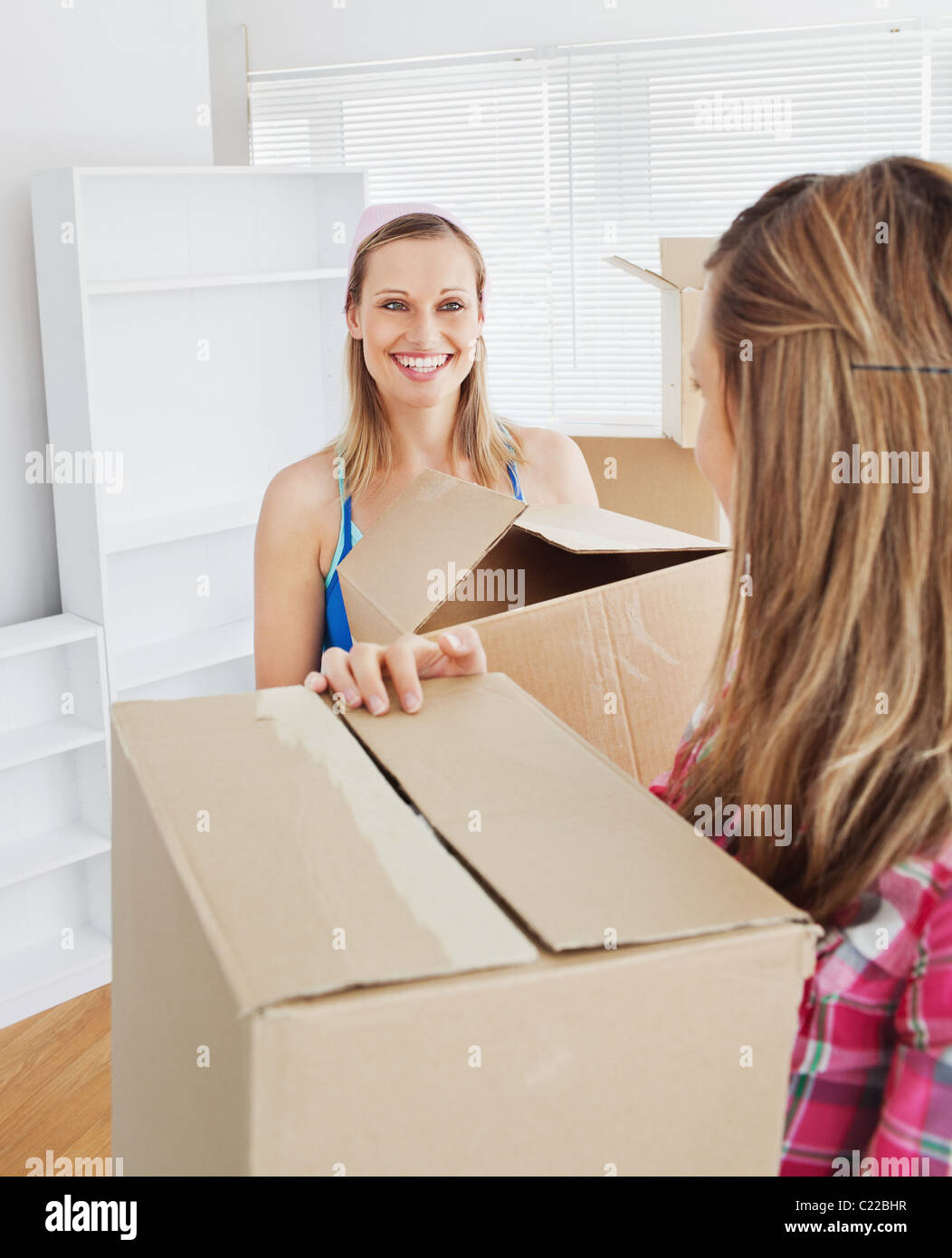 Two radiant female friends holding boxes after moving Stock Photo - Alamy