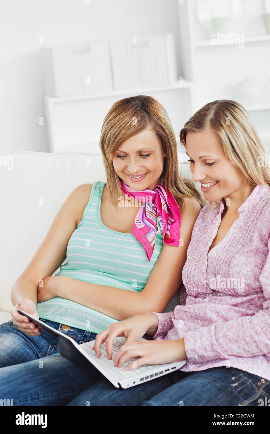 Positive friends using a laptop Stock Photo - Alamy