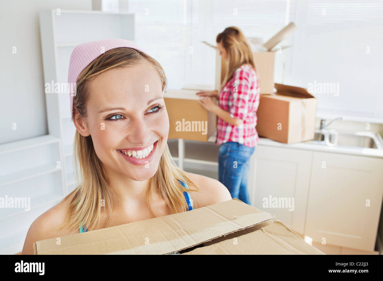 Two joyful women carrying boxes at home Stock Photo - Alamy