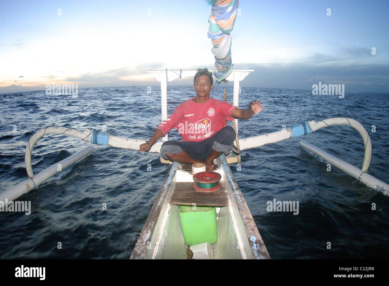 Balinese man balancing in fishing boat at sunrise Stock Photo - Alamy