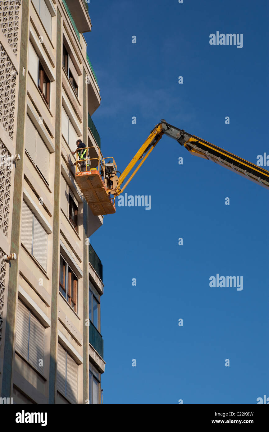 worker on elevator platform lift renewing external facade wall building ...