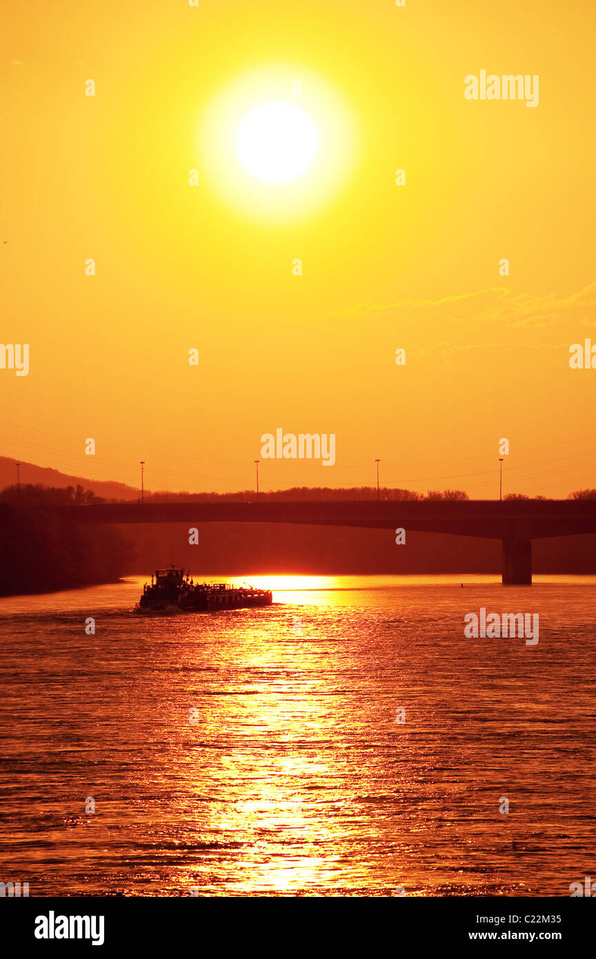 push boat with cargo sailing towards beautiful sunset on the Danube ...