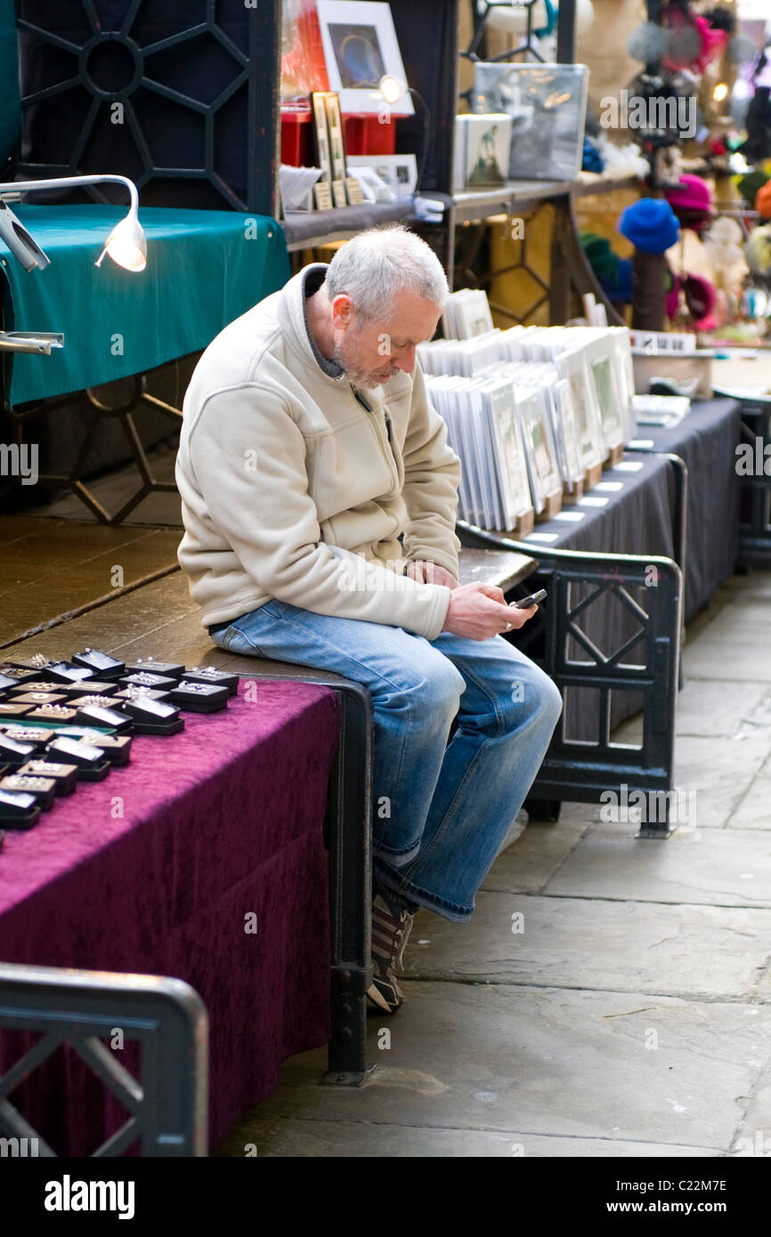 Covent Garden , bored grey or gray haired man , stall holder seated ...