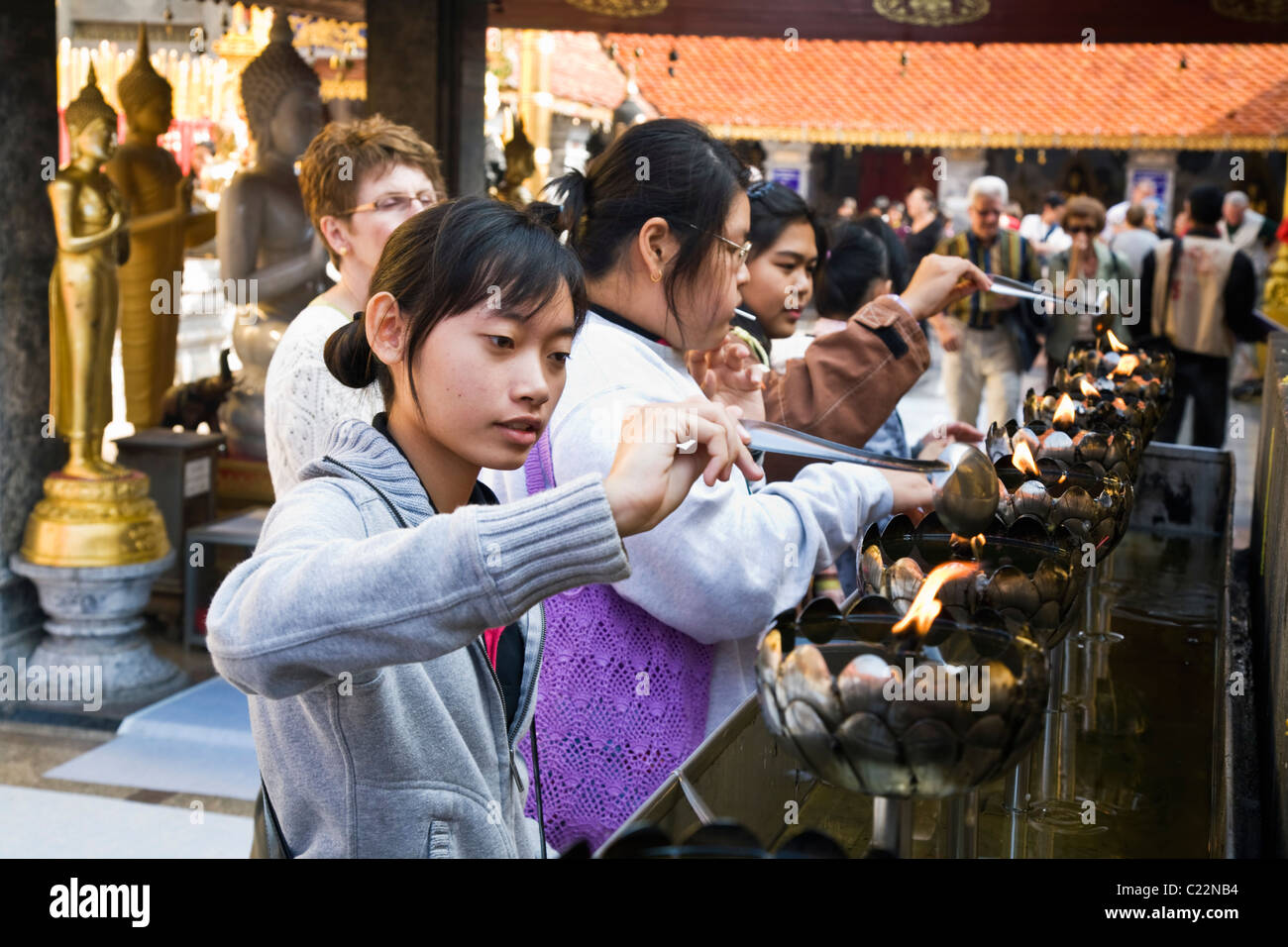 Buddhist pilgrims performing a libation (ritual pouring of oil) at Wat ...
