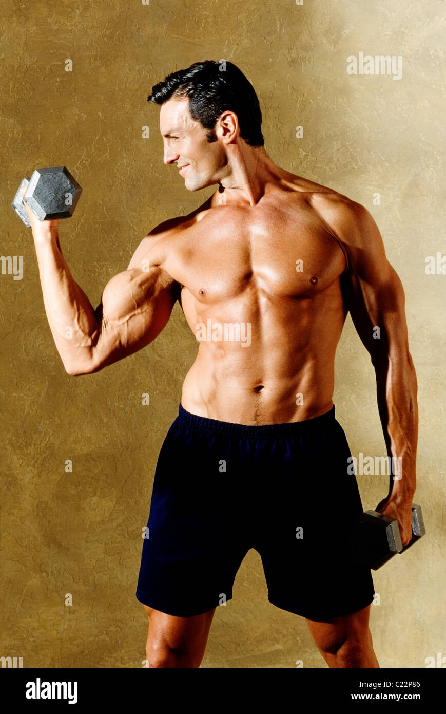 Young man lifting weights,laughing having fun, studio background ...
