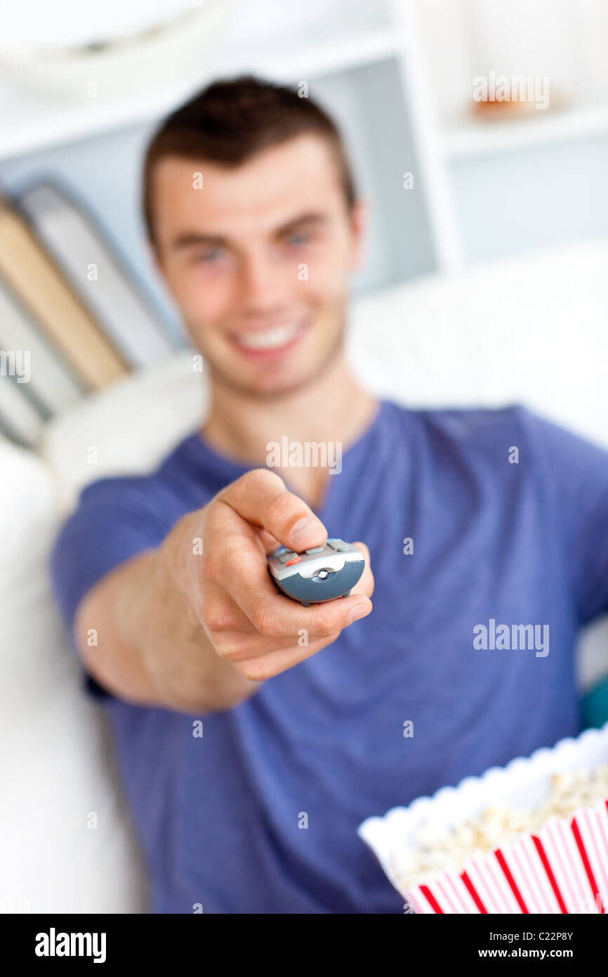 Positive caucasian man holding a remote looking at the camera in the ...