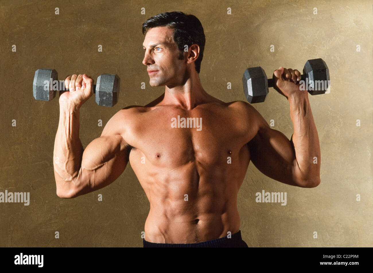 Young man lifting weights,laughing having fun, studio background ...