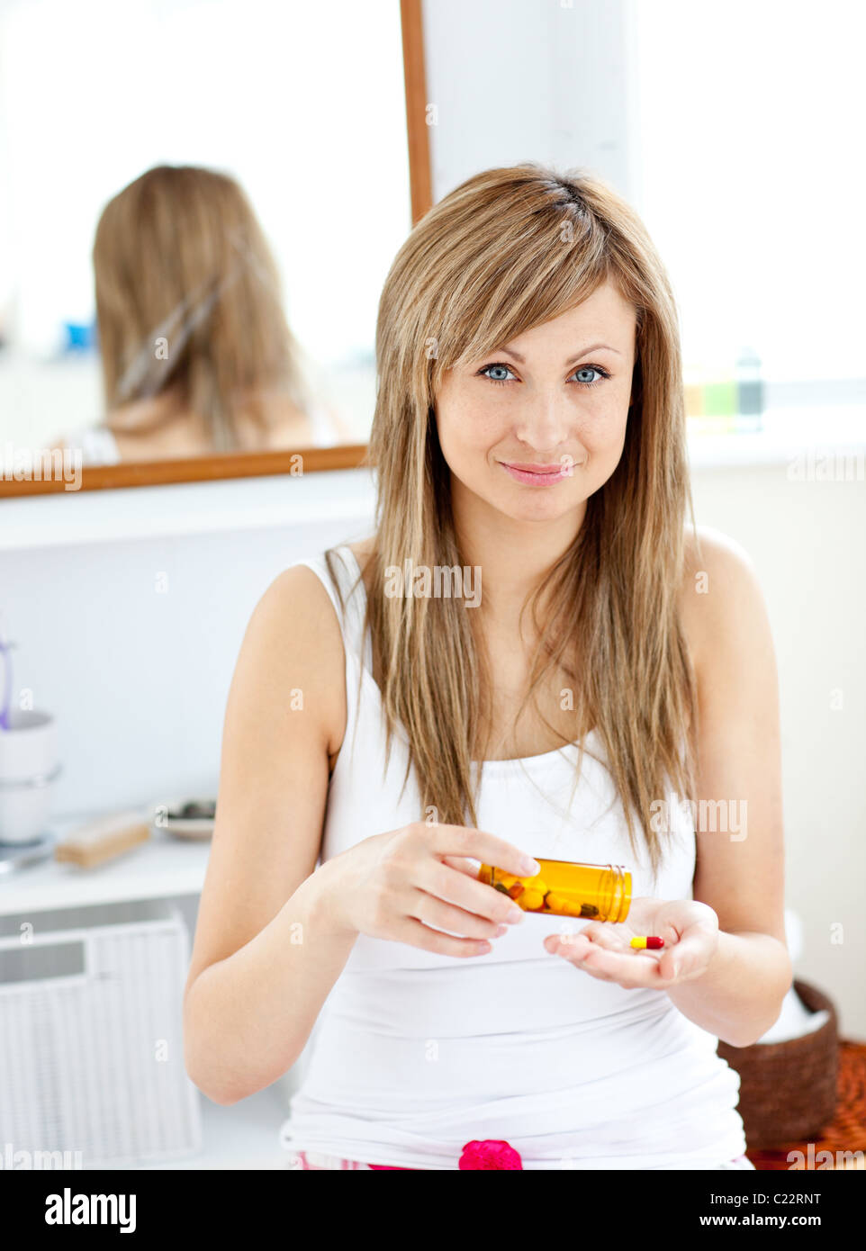 Blond woman taking pills looking at the camera in the bathroom Stock ...