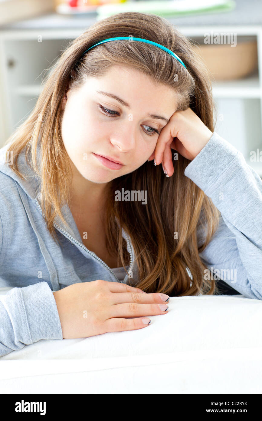 Dejected young woman sitting at the table in the kitchen Stock Photo ...