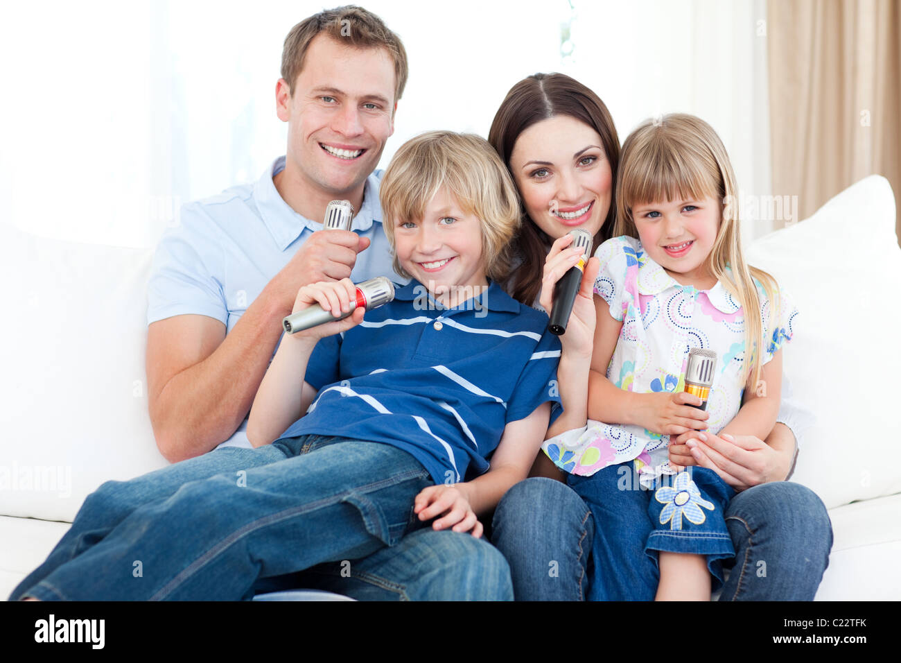 Smiling young family singing a karaoke together Stock Photo - Alamy