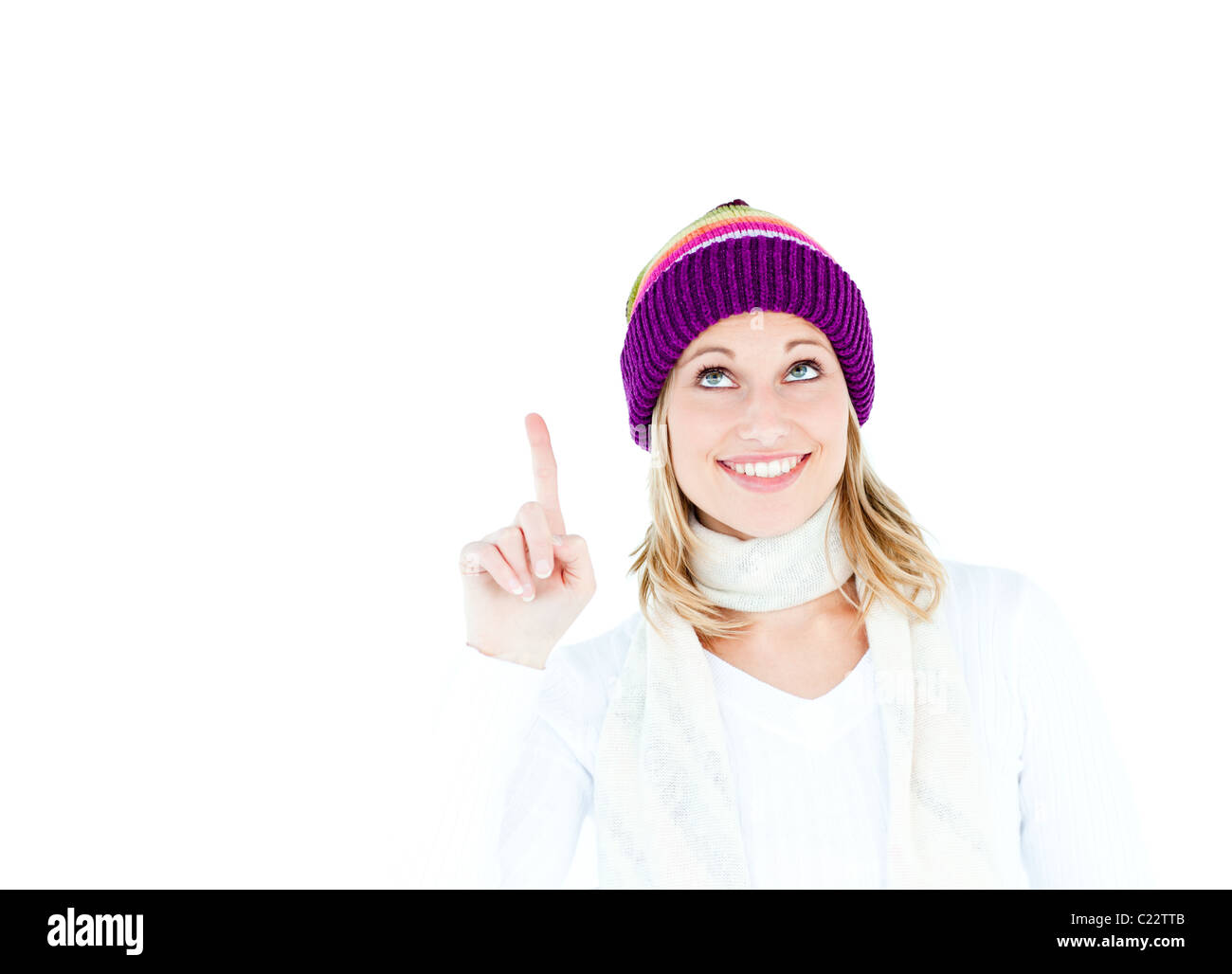 Young woman wearing a colorful hat pointing upwards with her finger ...