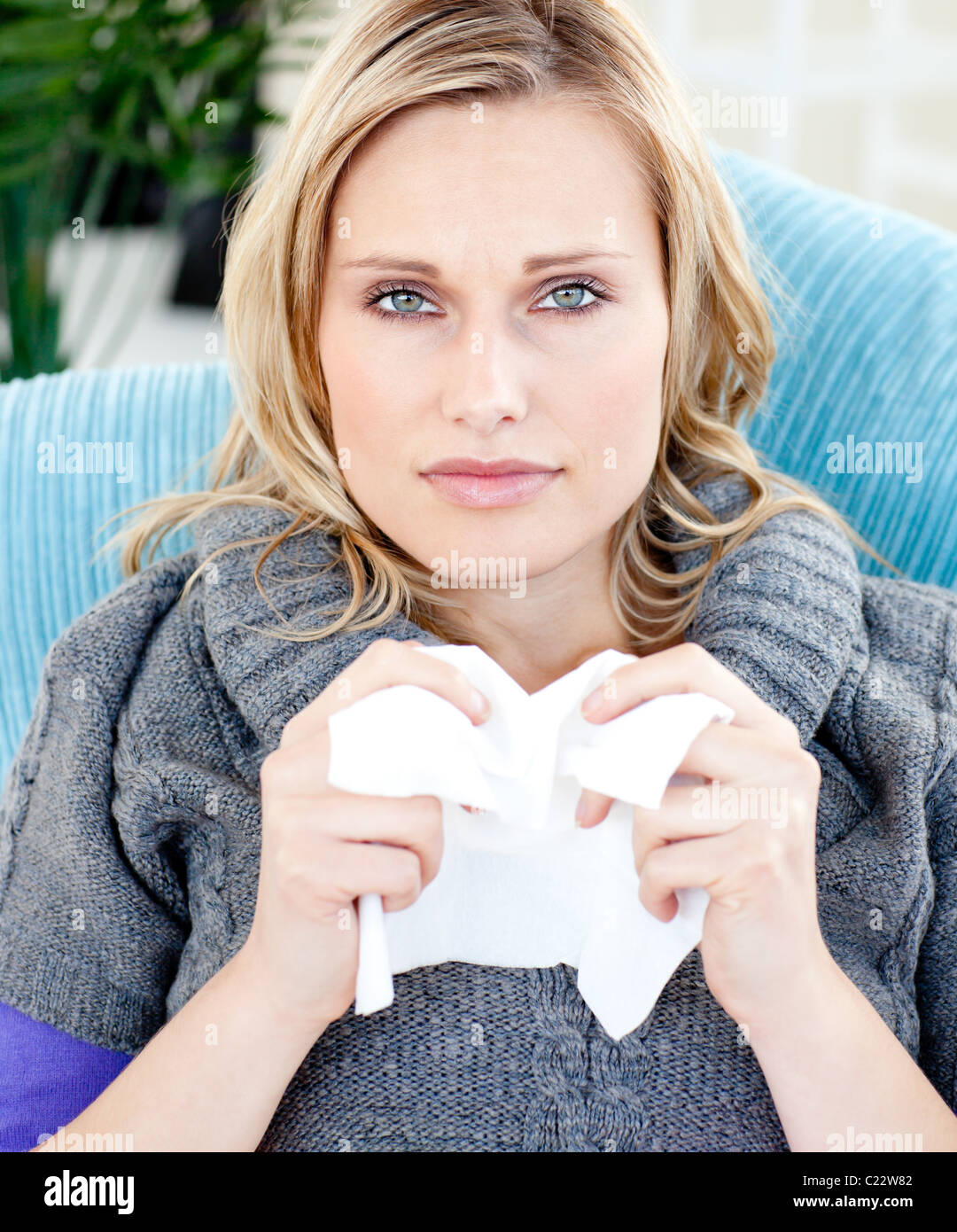 Diseased woman using a tissue sitting on a sofa Stock Photo - Alamy