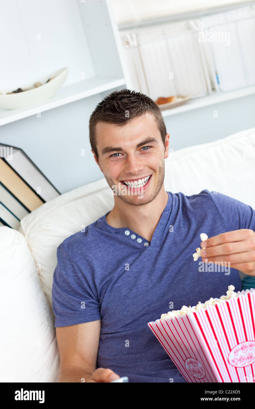 Handsome man eating popcorn on a sofa Stock Photo - Alamy