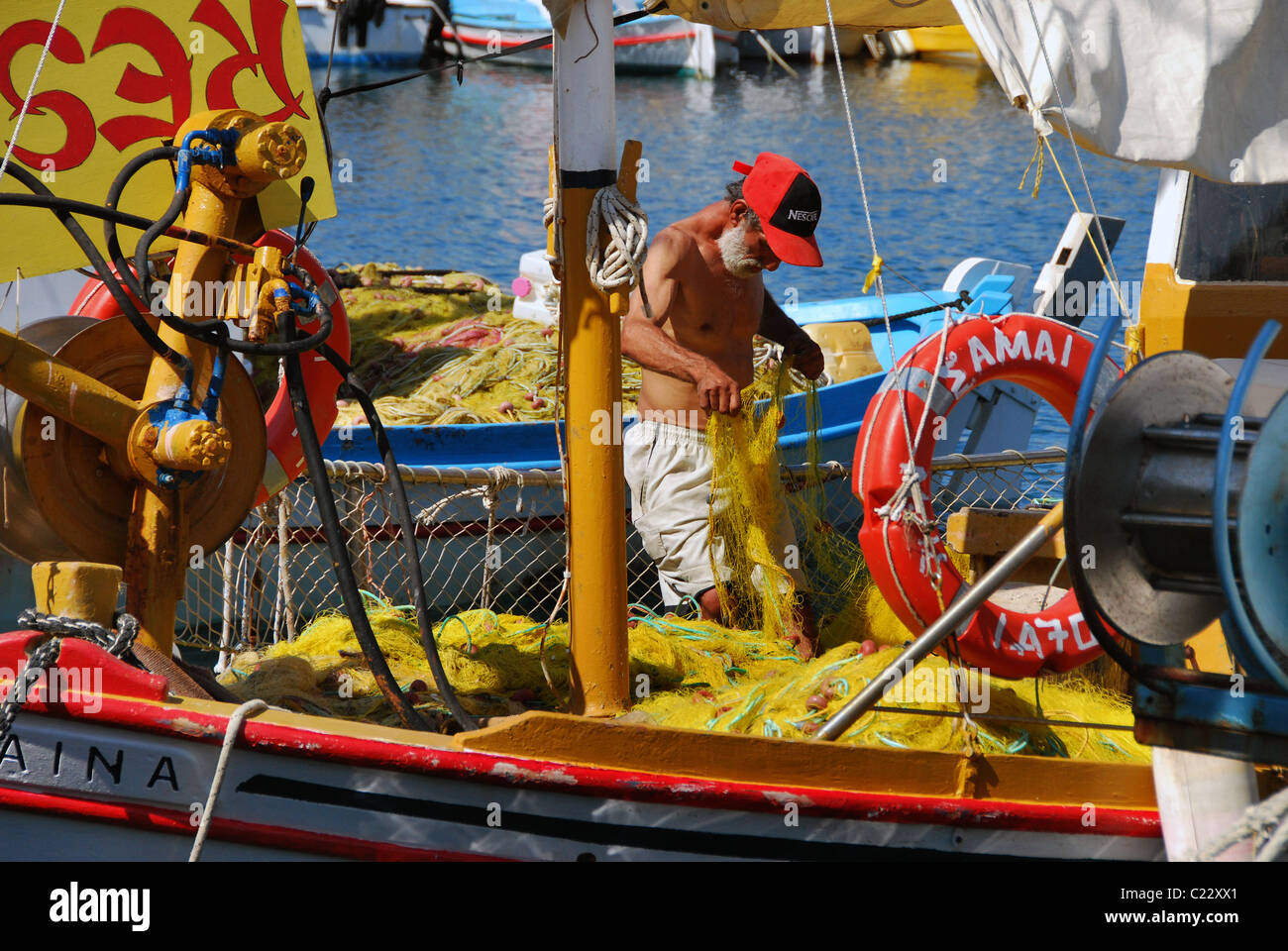 Fisherman at work, greek fishing boats in harbour, village of Aghios ...