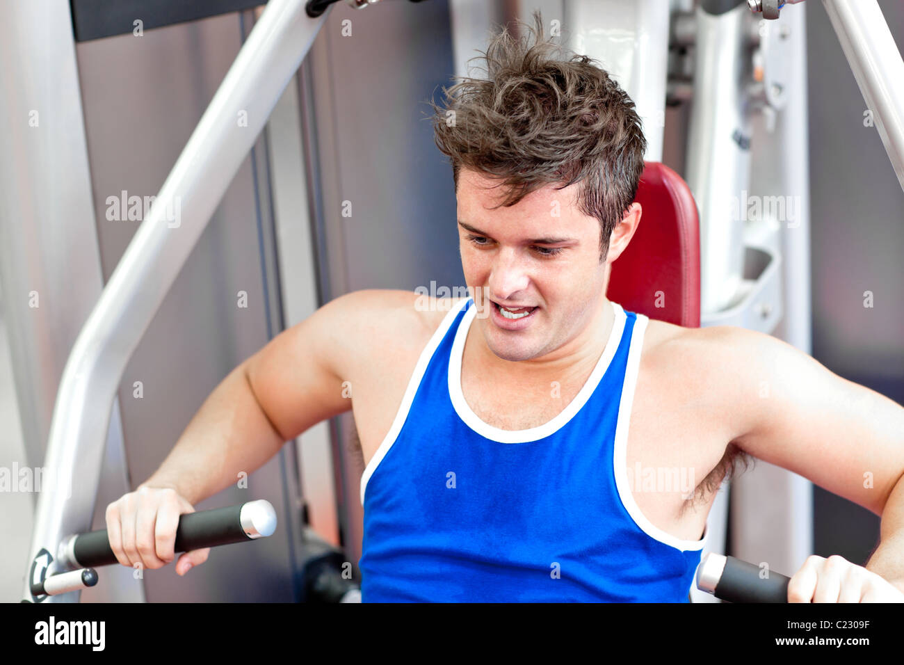Athletic young man using a bench press Stock Photo - Alamy