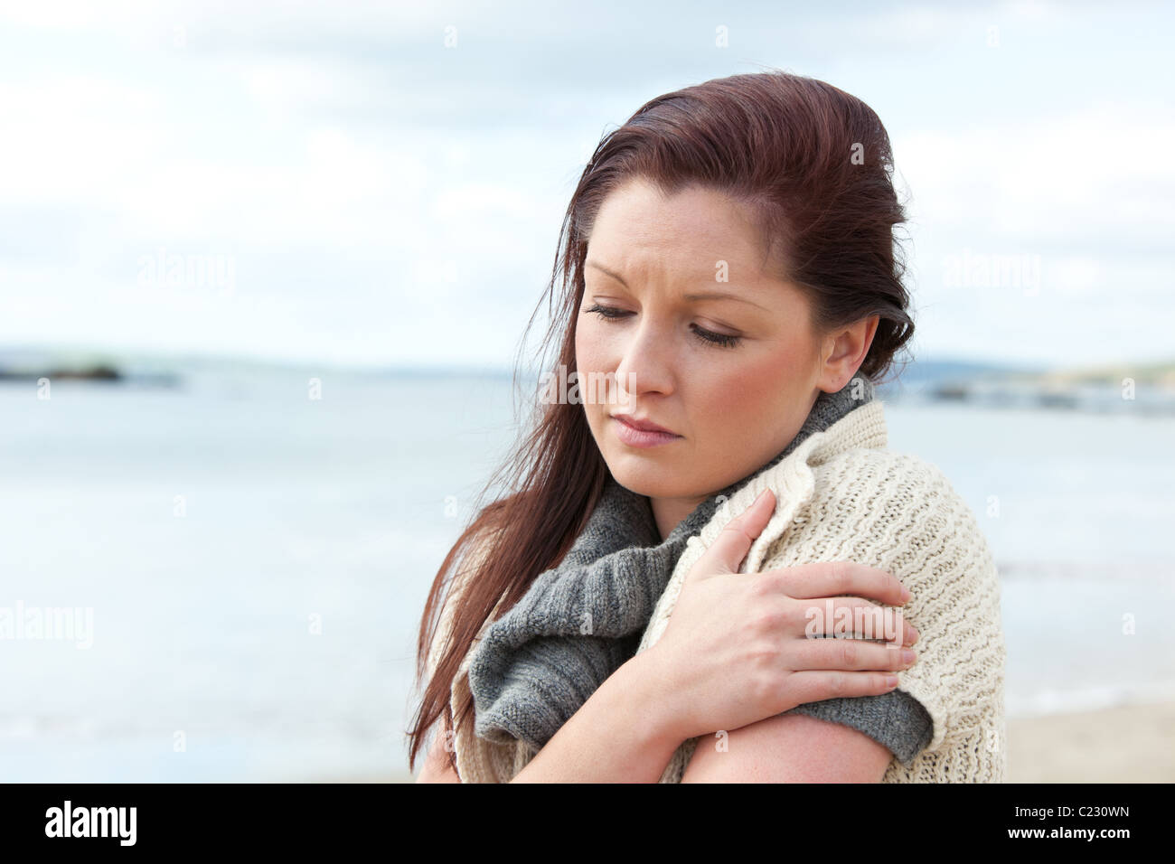 Worried woman wearing hat and scarf on the beach Stock Photo - Alamy