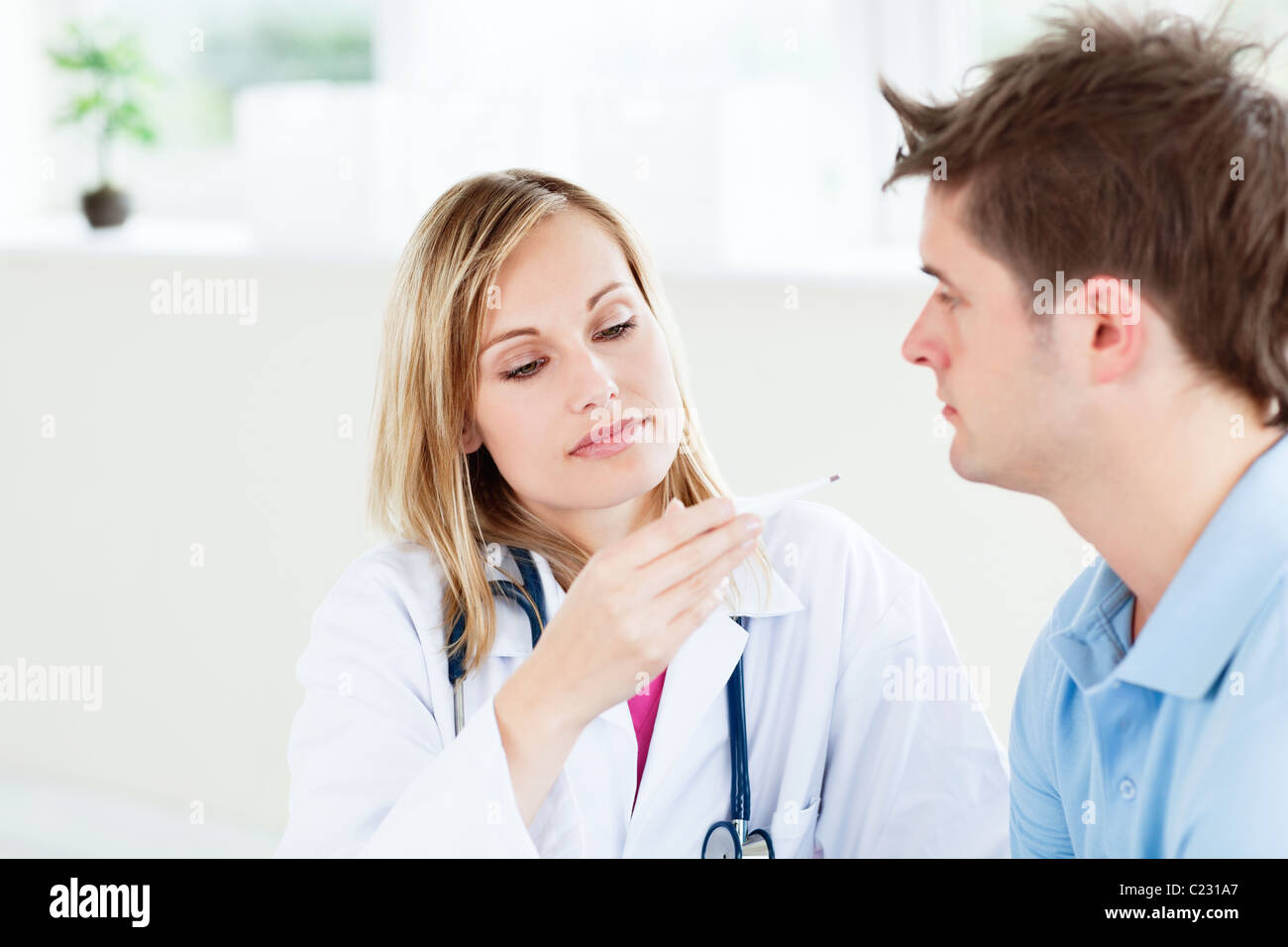 Concentrated female doctor looking at patient Stock Photo - Alamy