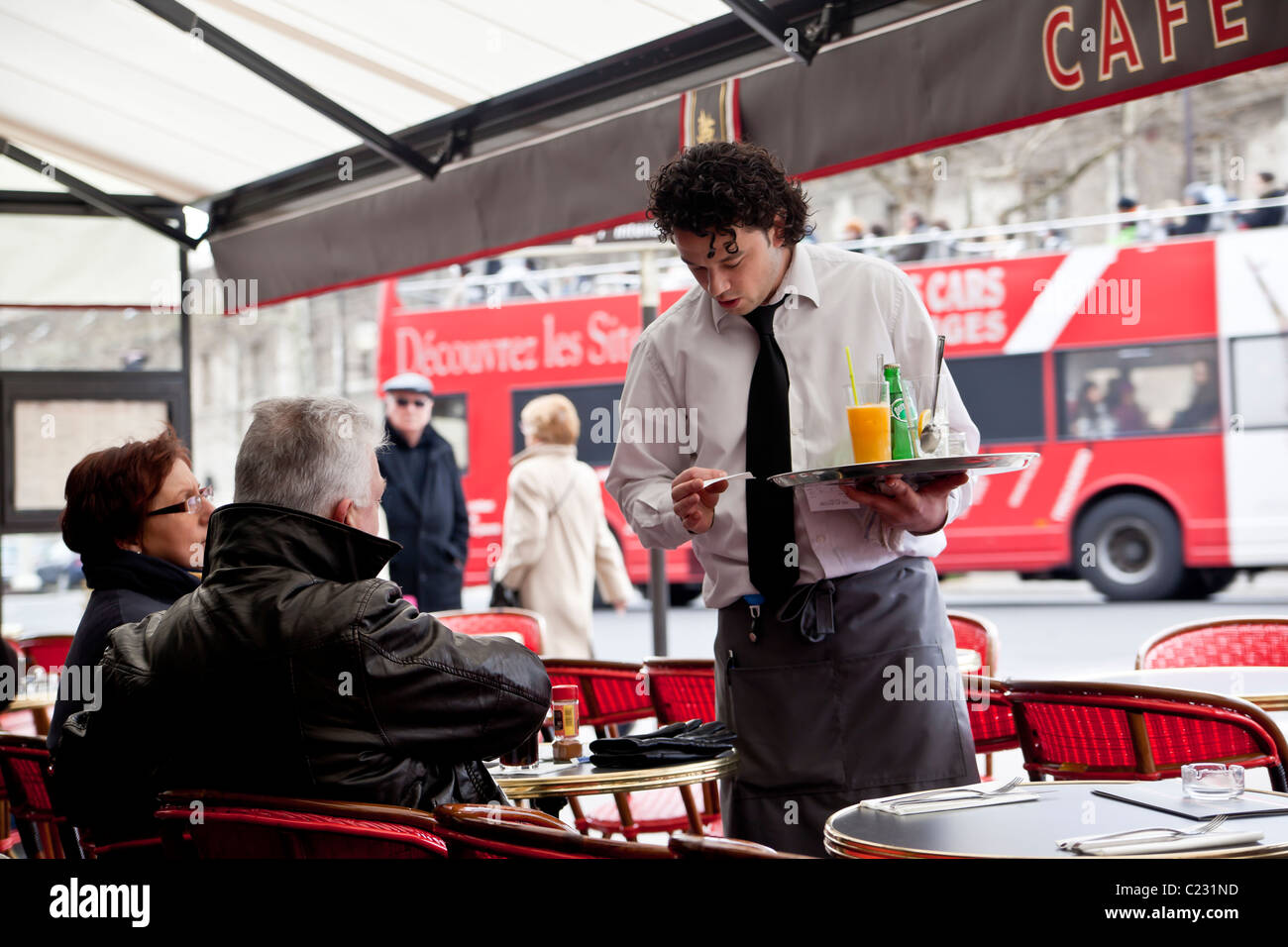 Waiter serving couple in a Paris sidewalk cafe; Paris, France. Charles ...