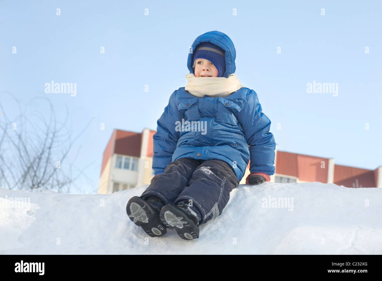 Young boy sitting in the snow Stock Photo - Alamy
