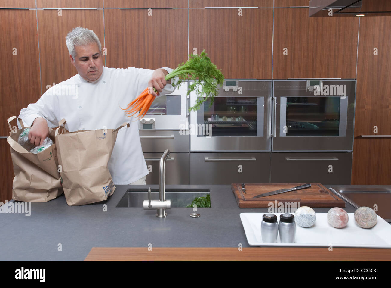 Mid- adult chef lifting carrots into sink Stock Photo - Alamy