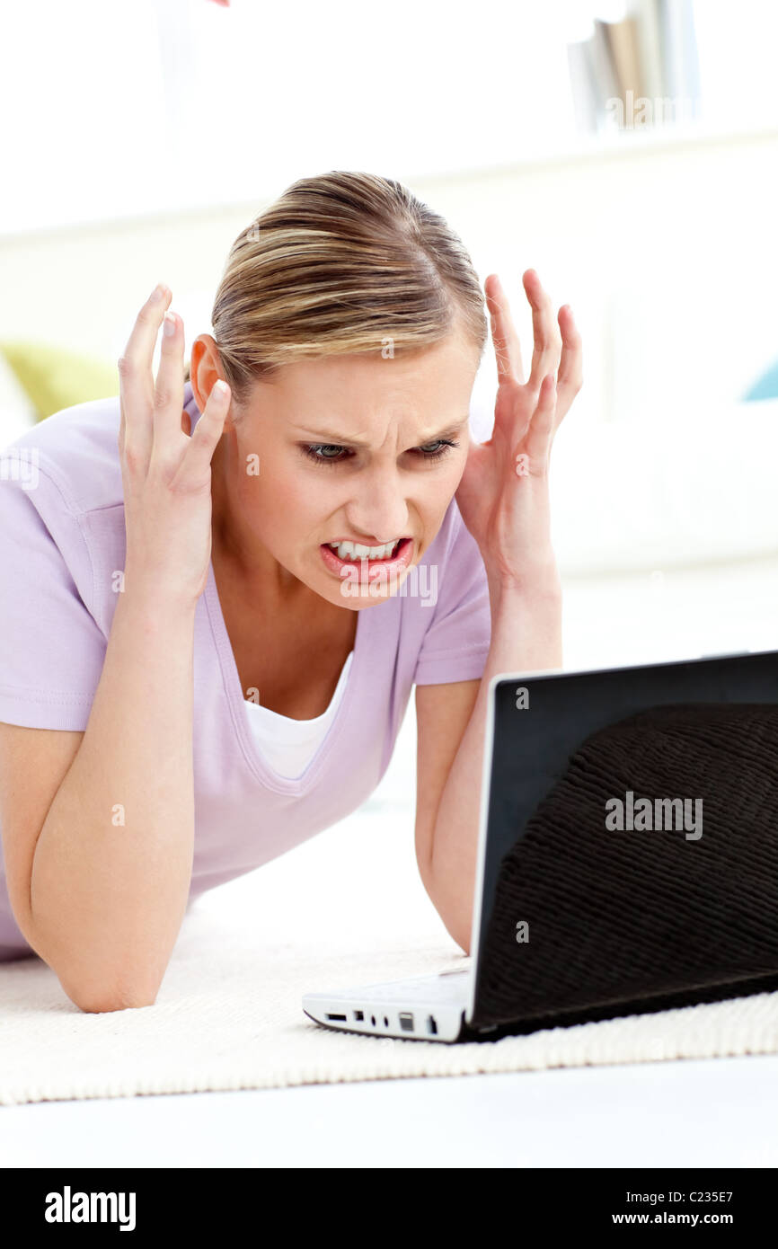 Angry young woman lying on the floor using her laptop Stock Photo - Alamy
