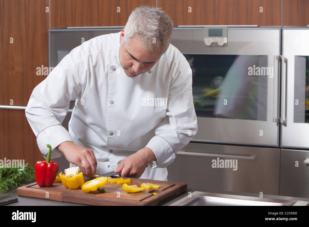 Mid- adult chef slices red and yellow bell peppers Stock Photo - Alamy