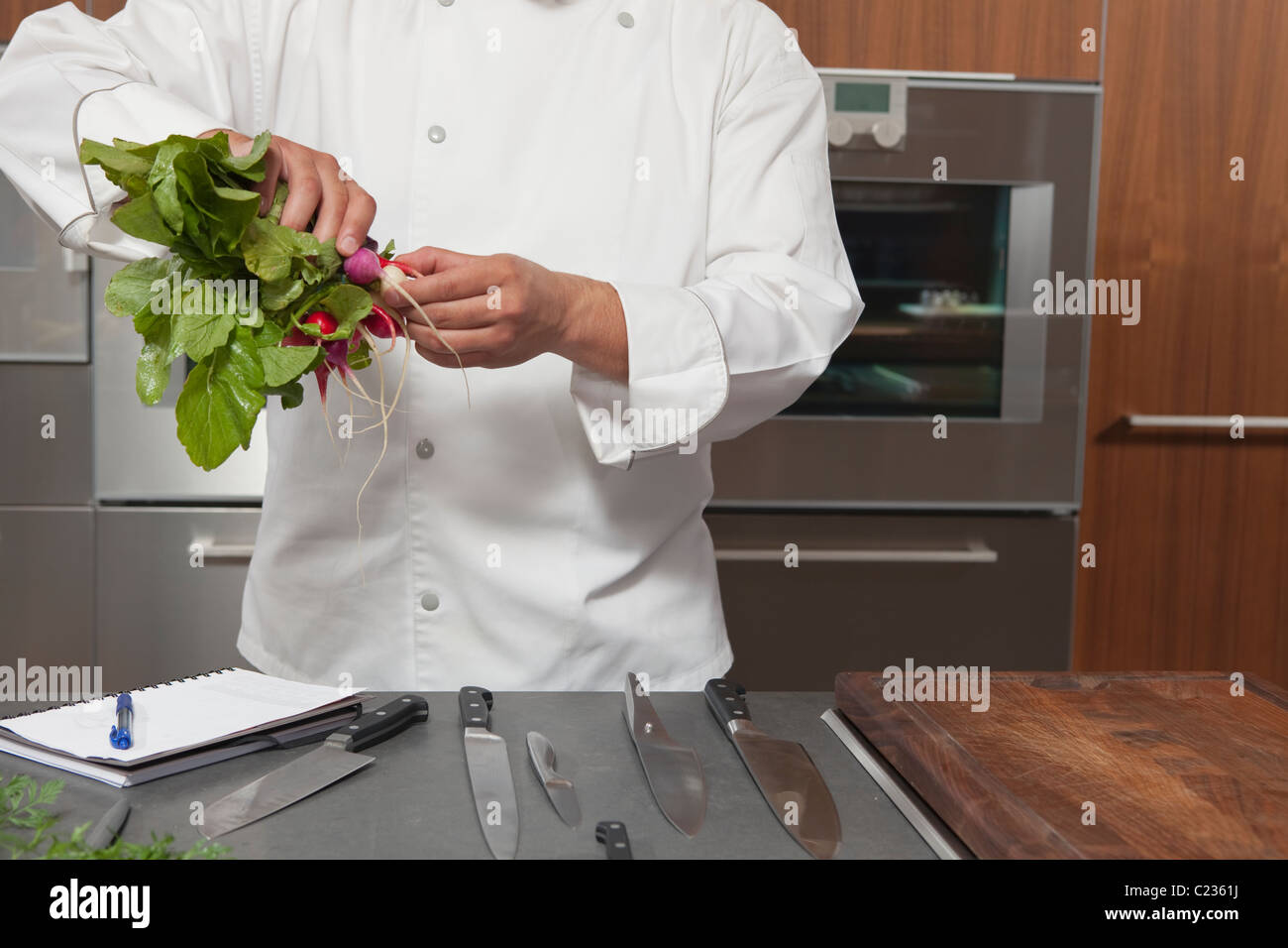 Mid- adult chef preparing radishes Stock Photo - Alamy