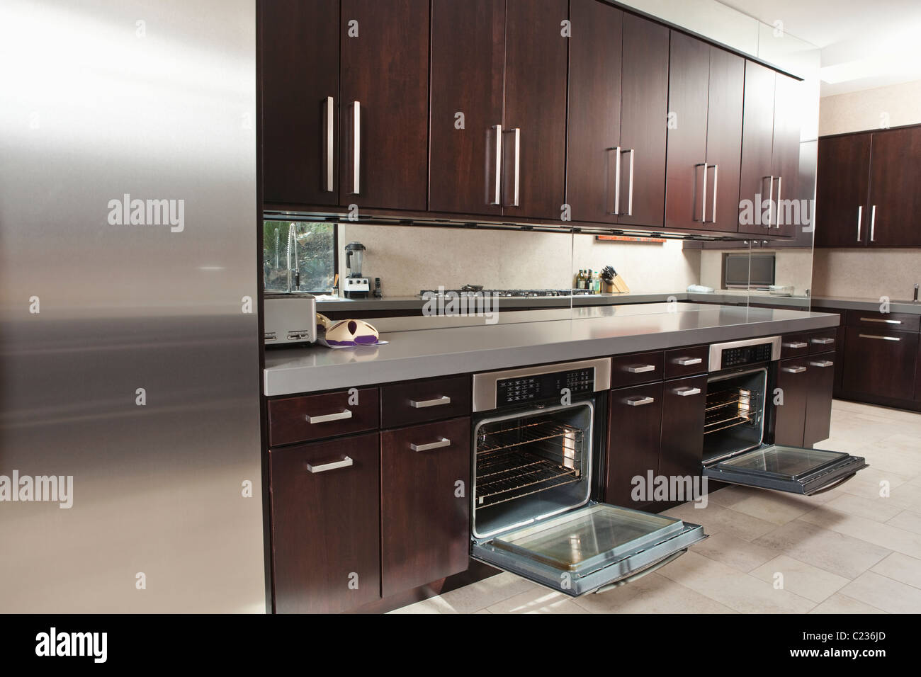 Dark wood kitchen with open oven doors Stock Photo - Alamy