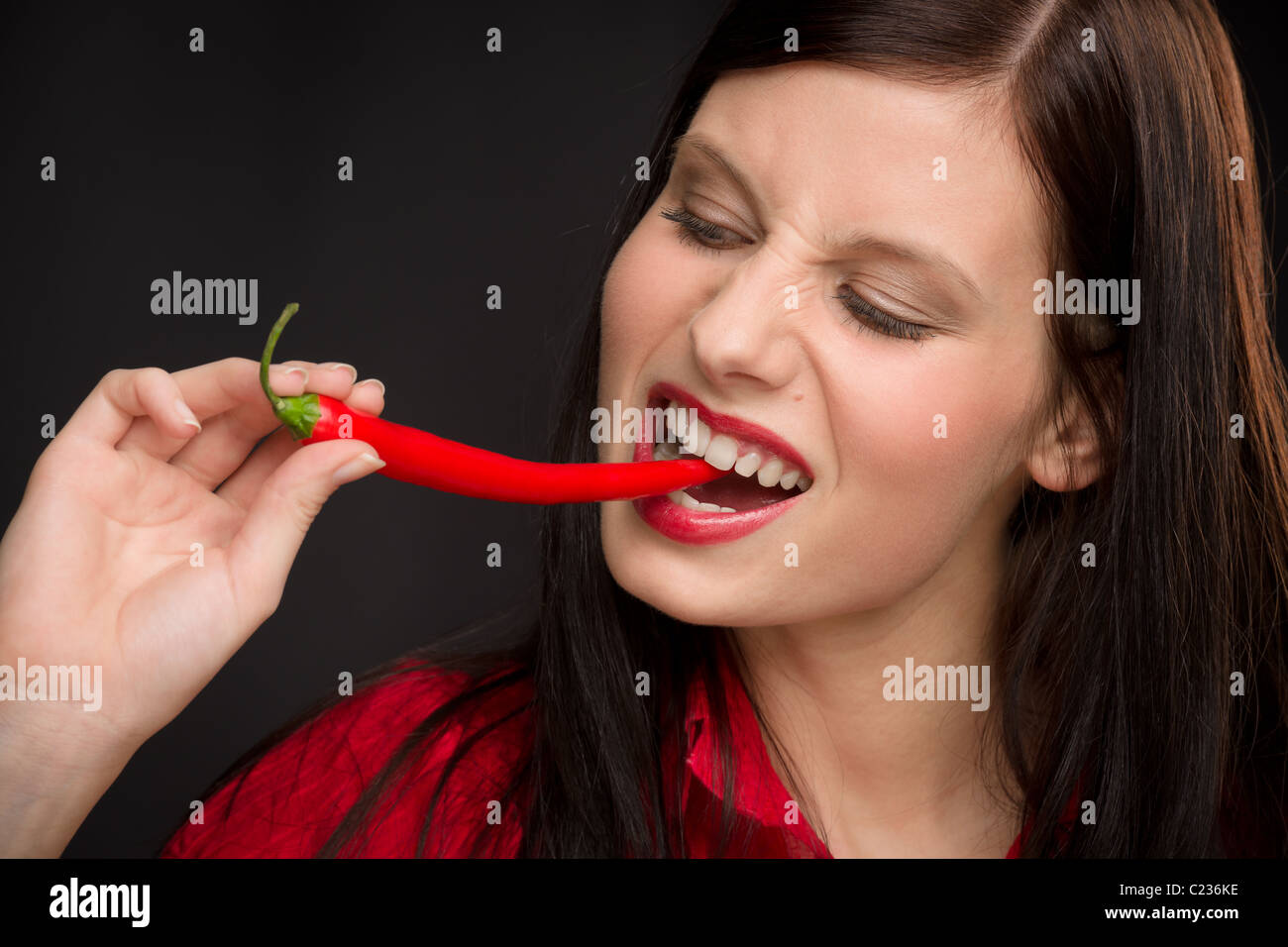 Chili pepper - portrait young woman bite red spicy vegetable Stock ...