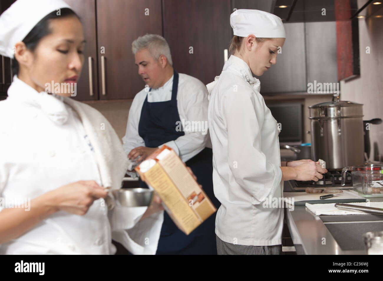 Three chefs work together in busy kitchen Stock Photo - Alamy