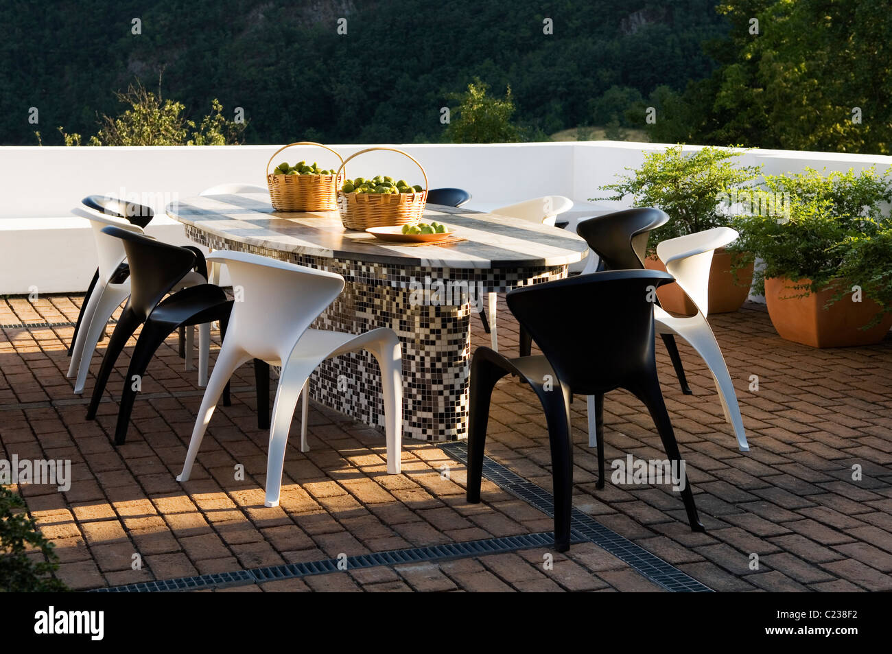 Designer Italian dining chairs around tiled table on brick floored ...