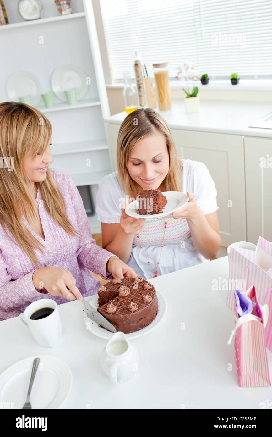 Delighted female friends eating a chocolate cake in the kitchen Stock ...