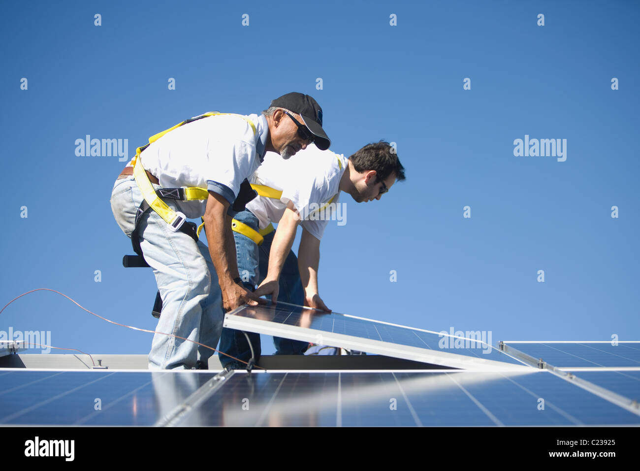 Two men lifting a solar panel Stock Photo - Alamy