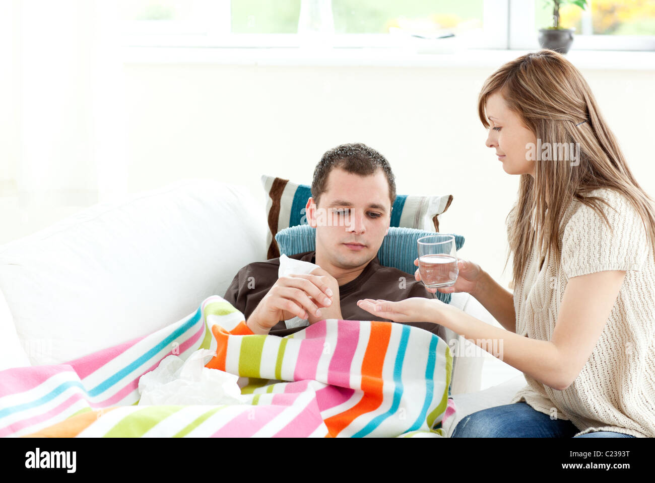 Caring girlfriend giving his sick boyfriend pill Stock Photo - Alamy