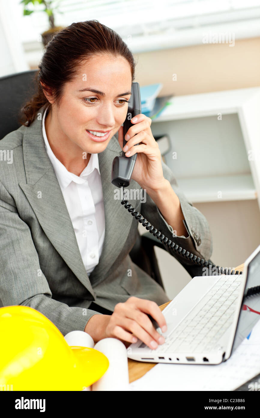 Female architect using her laptop while talking on phone Stock Photo ...