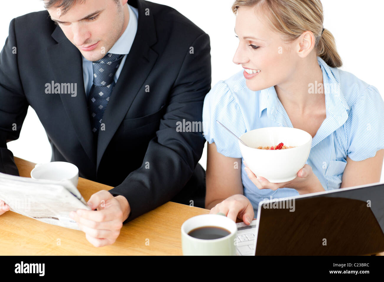 Happy couple of businesspeople having breakfast reading the newspaper ...