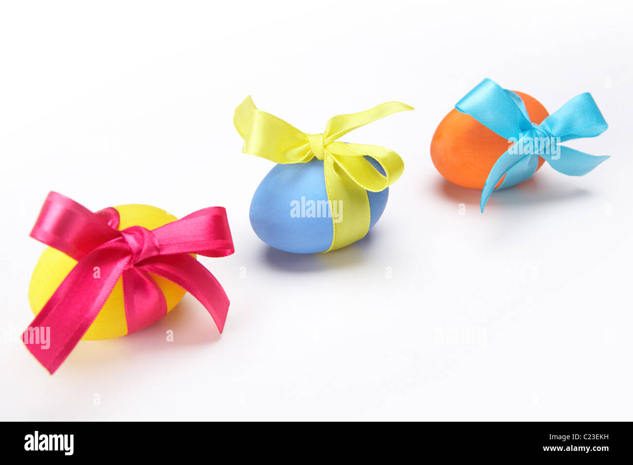 Image of three multicolored eggs tied by silk ribbons on white ...