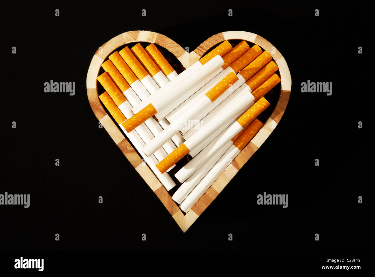 Cigarettes in heart shape against black background Stock Photo - Alamy