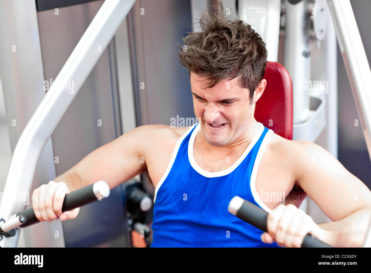 Muscular young man using a bench press Stock Photo - Alamy