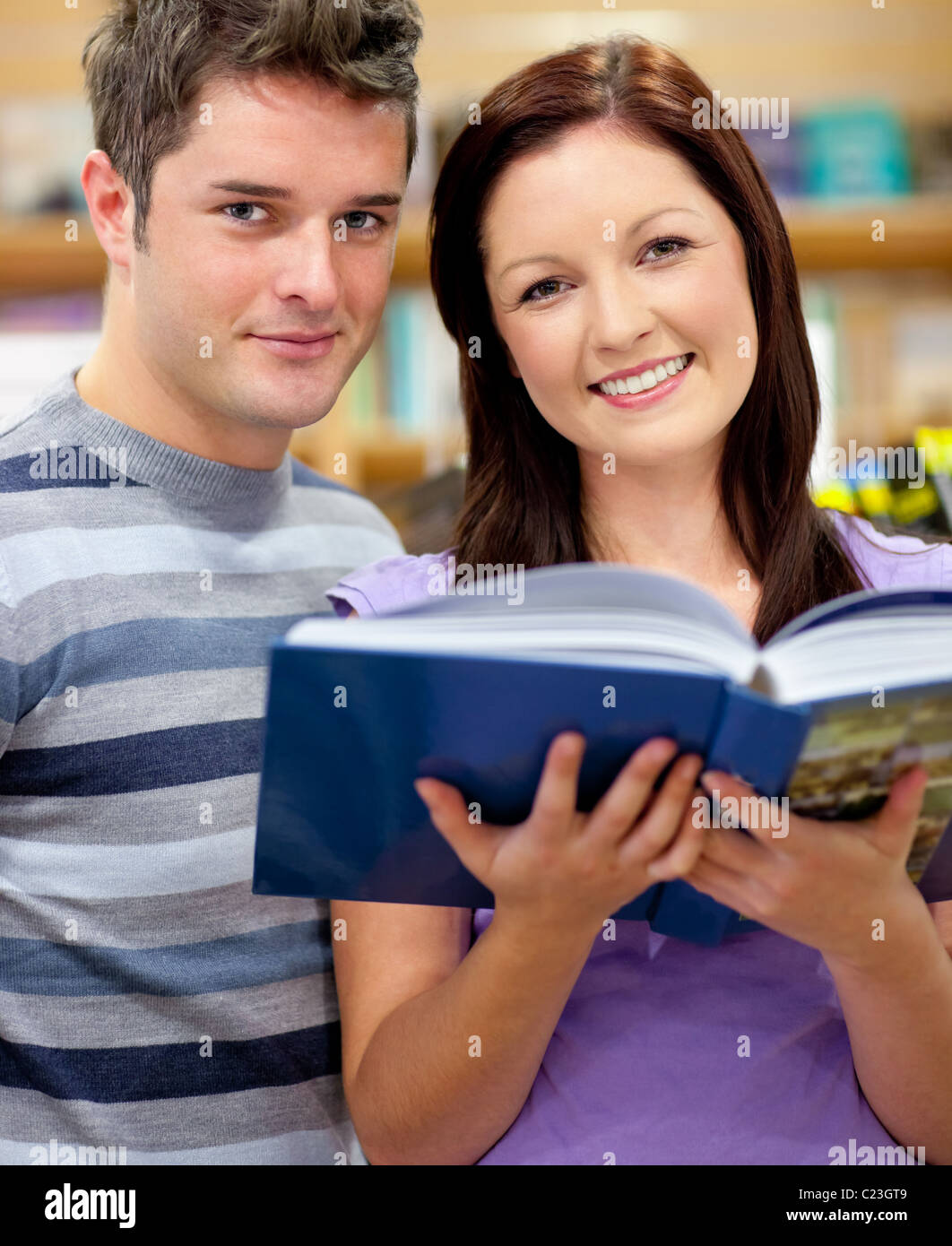Bright couple of students reading a book Stock Photo - Alamy