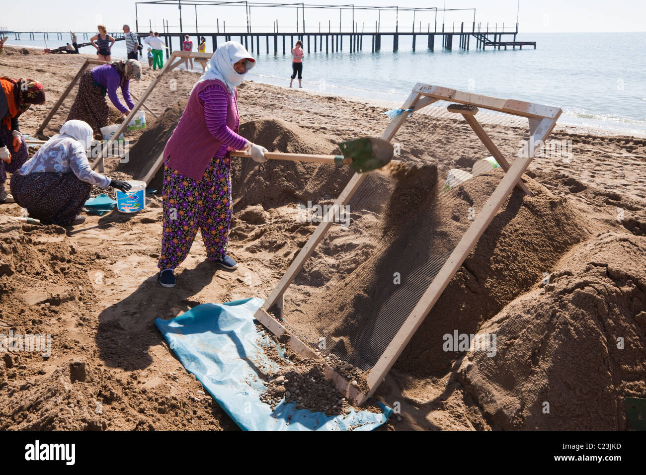 Turkish women working on the beach at Belek,Turkey, cleaning the sand ...