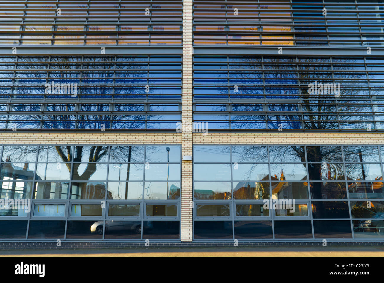 Glass sided modern office building with reflections of the sounding ...