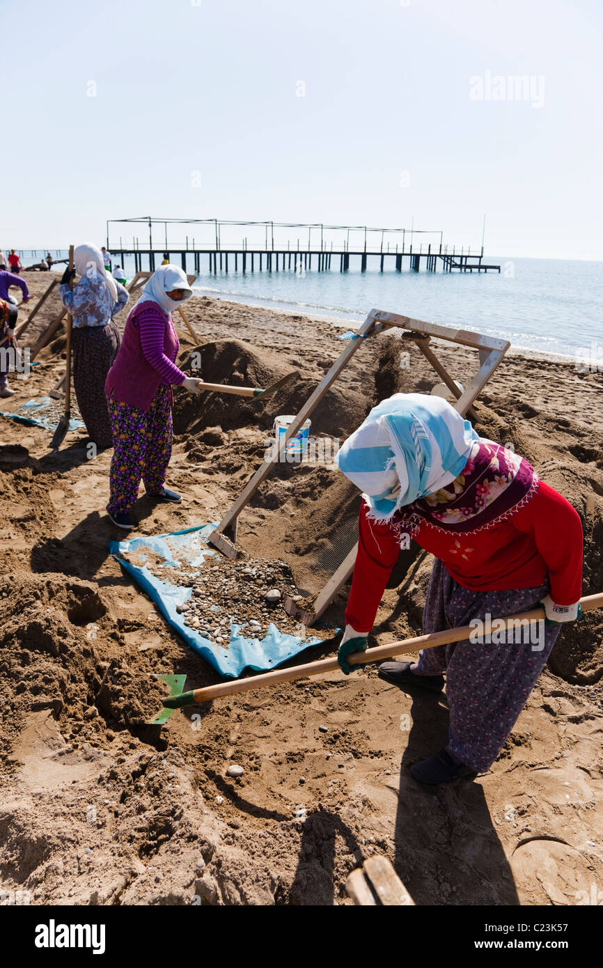 Turkish women working on the beach at Belek,Turkey, cleaning the sand ...