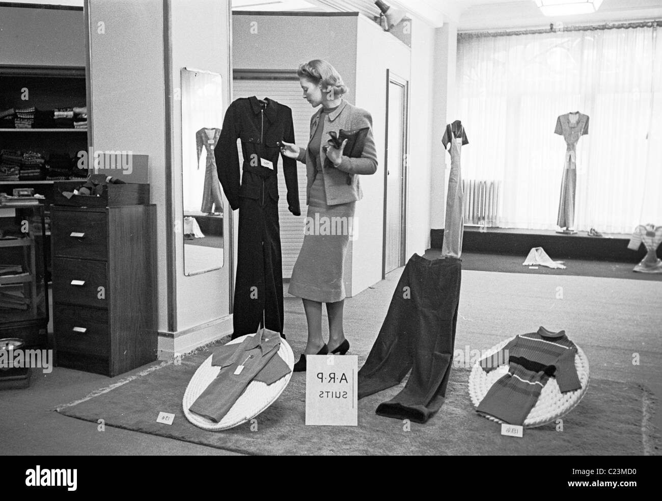 1940s, war time fashion, elegantly dressed lady examines the clothes ...