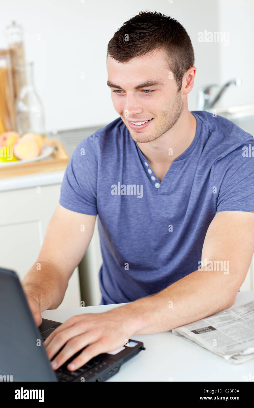 Positive young man using his laptop in the kitchen Stock Photo - Alamy